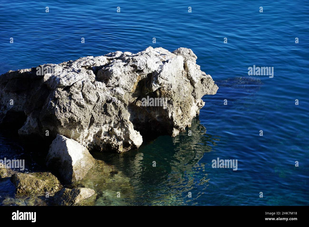 A large limestone rock in the sea and its reflection in the seawater ...