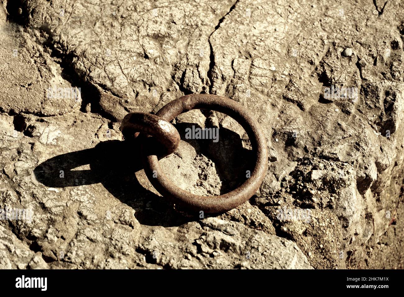 Rusty old iron round copper-colored hook for mooring ships and boats on the background of rough ...