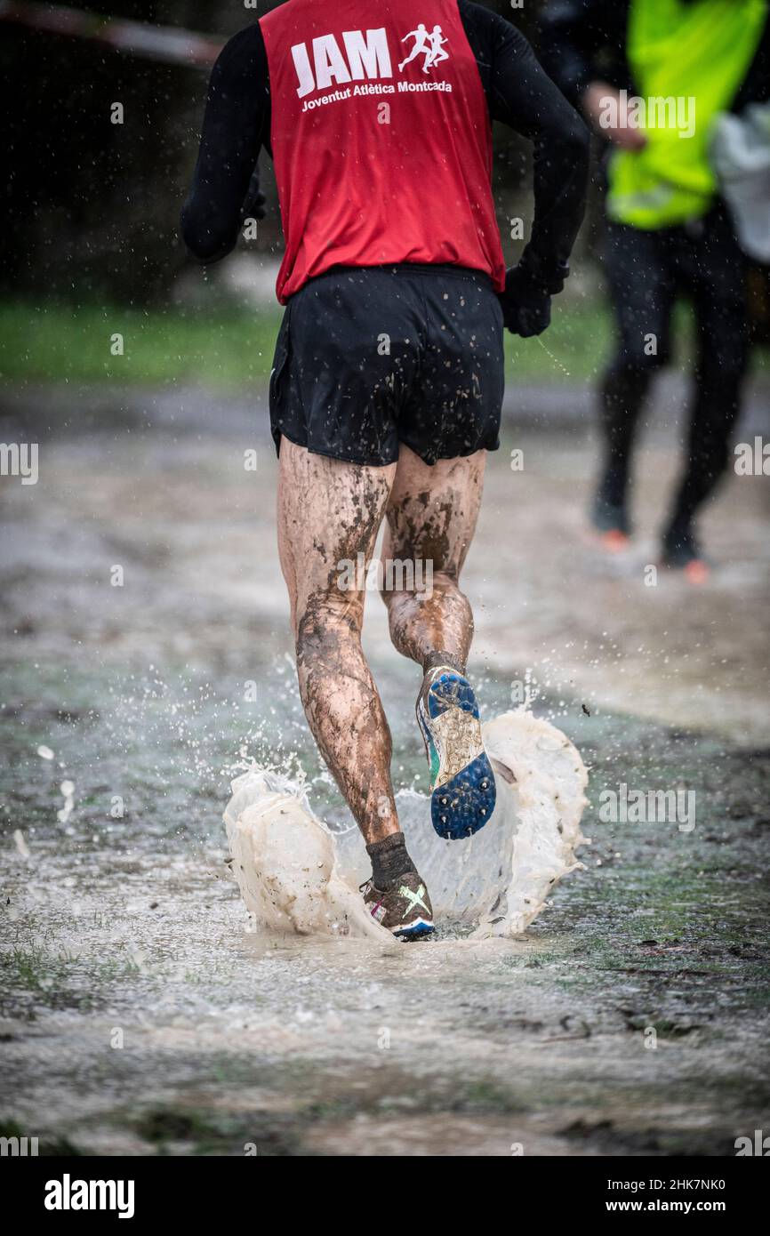 Athlete's legs running in a Cross Country between water and mud, pure ...