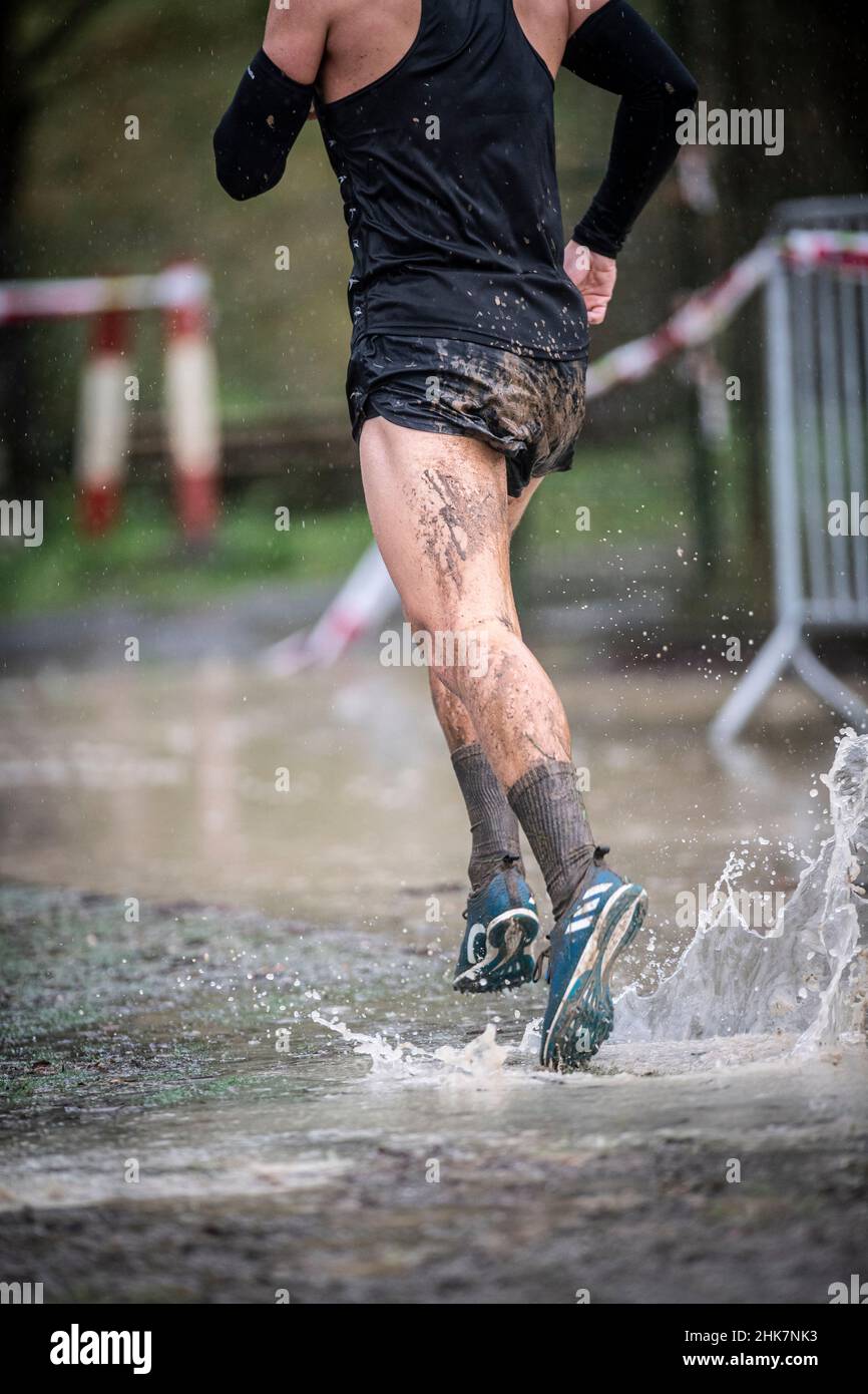Athlete's legs running in a Cross Country between water and mud, pure ...