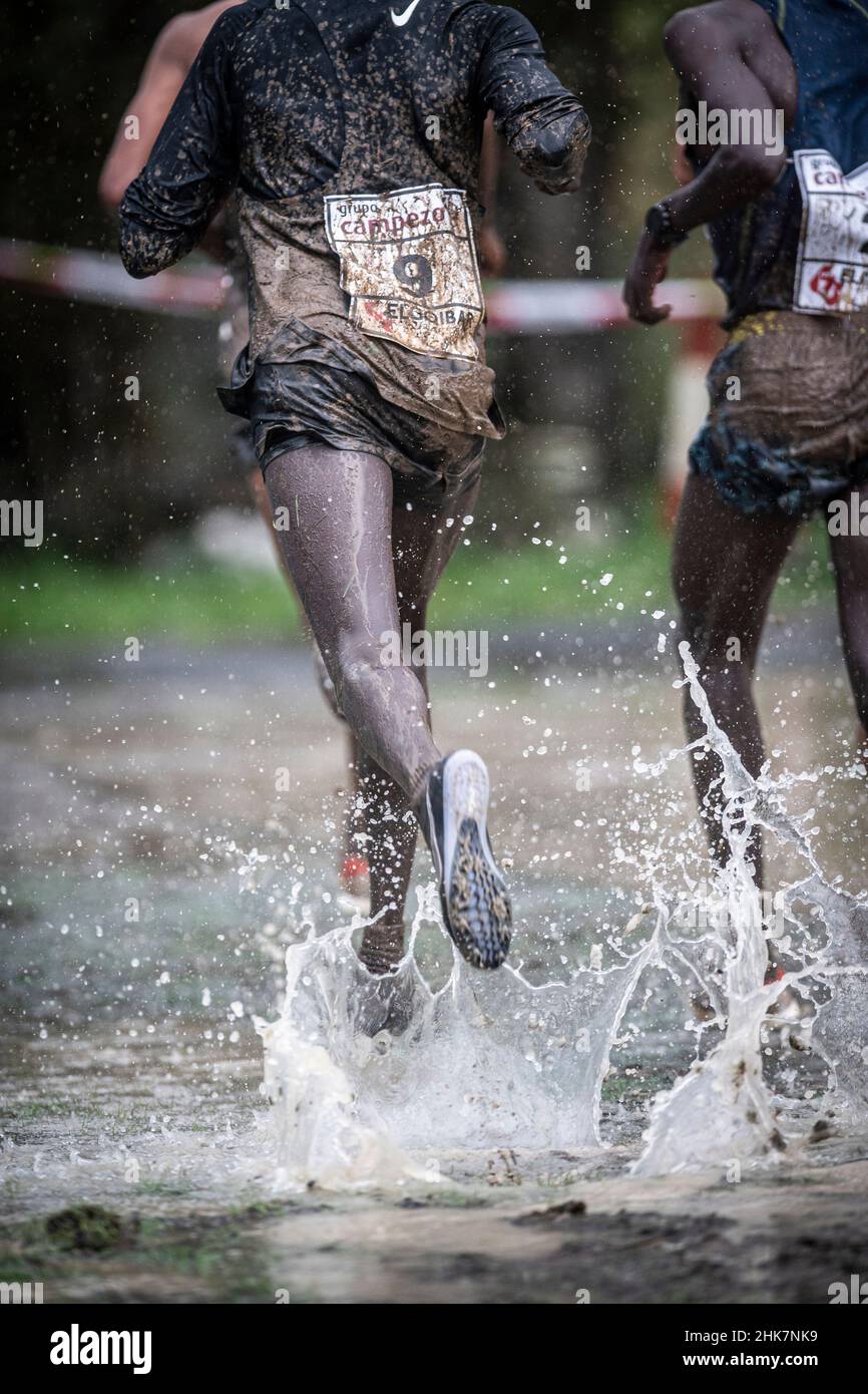Athlete's legs running in a Cross Country between water and mud, pure ...