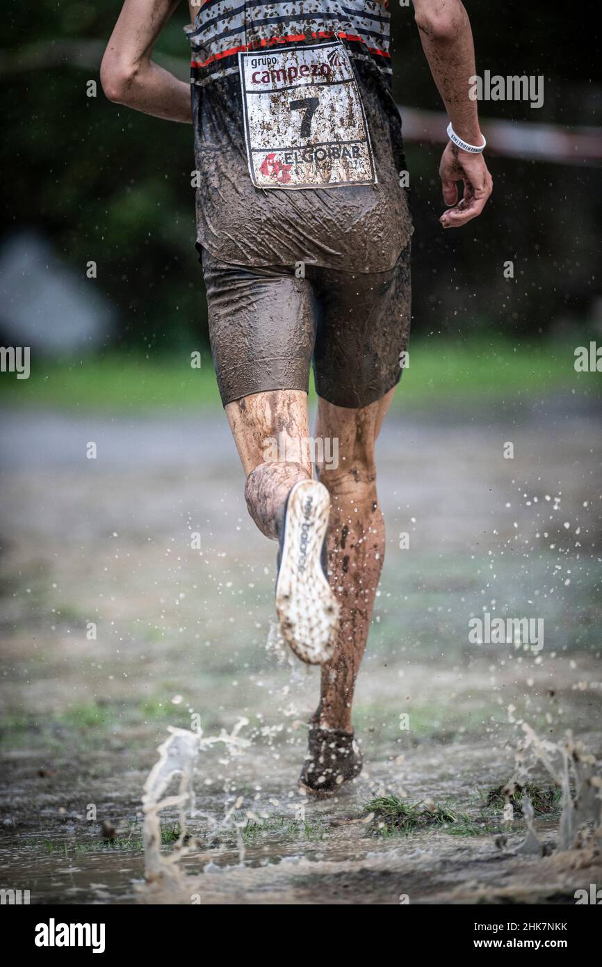 Athlete's legs running in a Cross Country between water and mud, pure ...