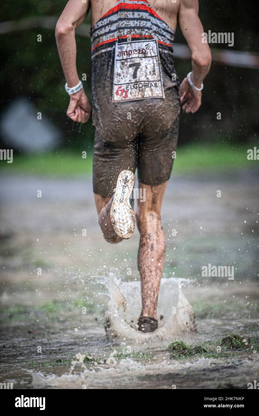 Athlete's legs running in a Cross Country between water and mud, pure ...