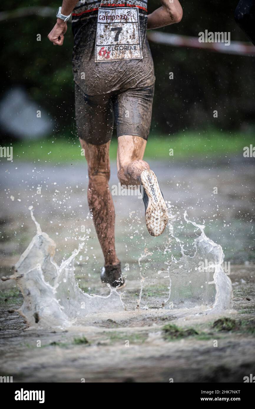 Athlete's legs running in a Cross Country between water and mud, pure ...