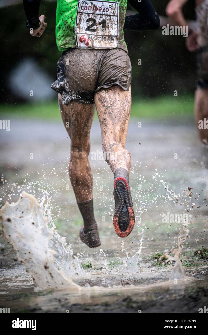 Athlete's legs running in a Cross Country between water and mud, pure ...