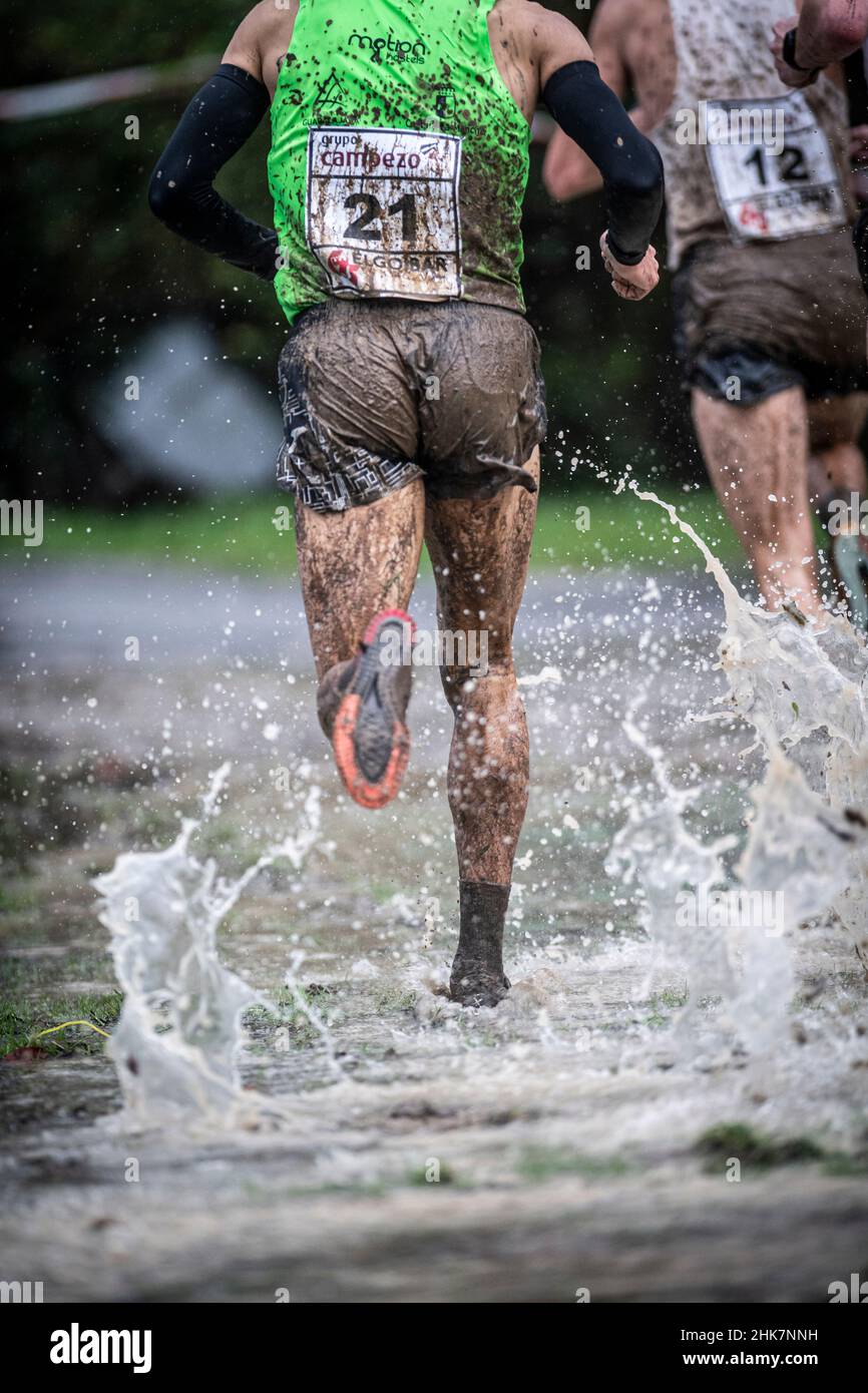 Athlete's legs running in a Cross Country between water and mud, pure ...