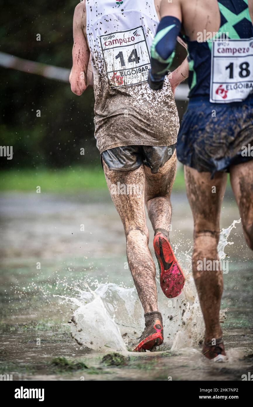 Athlete's legs running in a Cross Country between water and mud, pure ...
