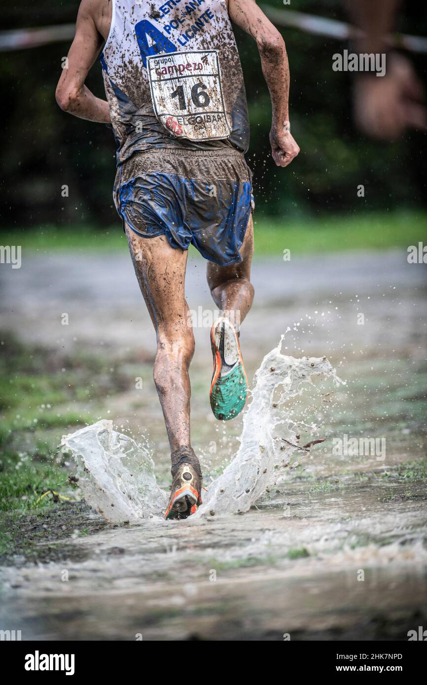 Athlete's legs running in a Cross Country between water and mud, pure ...