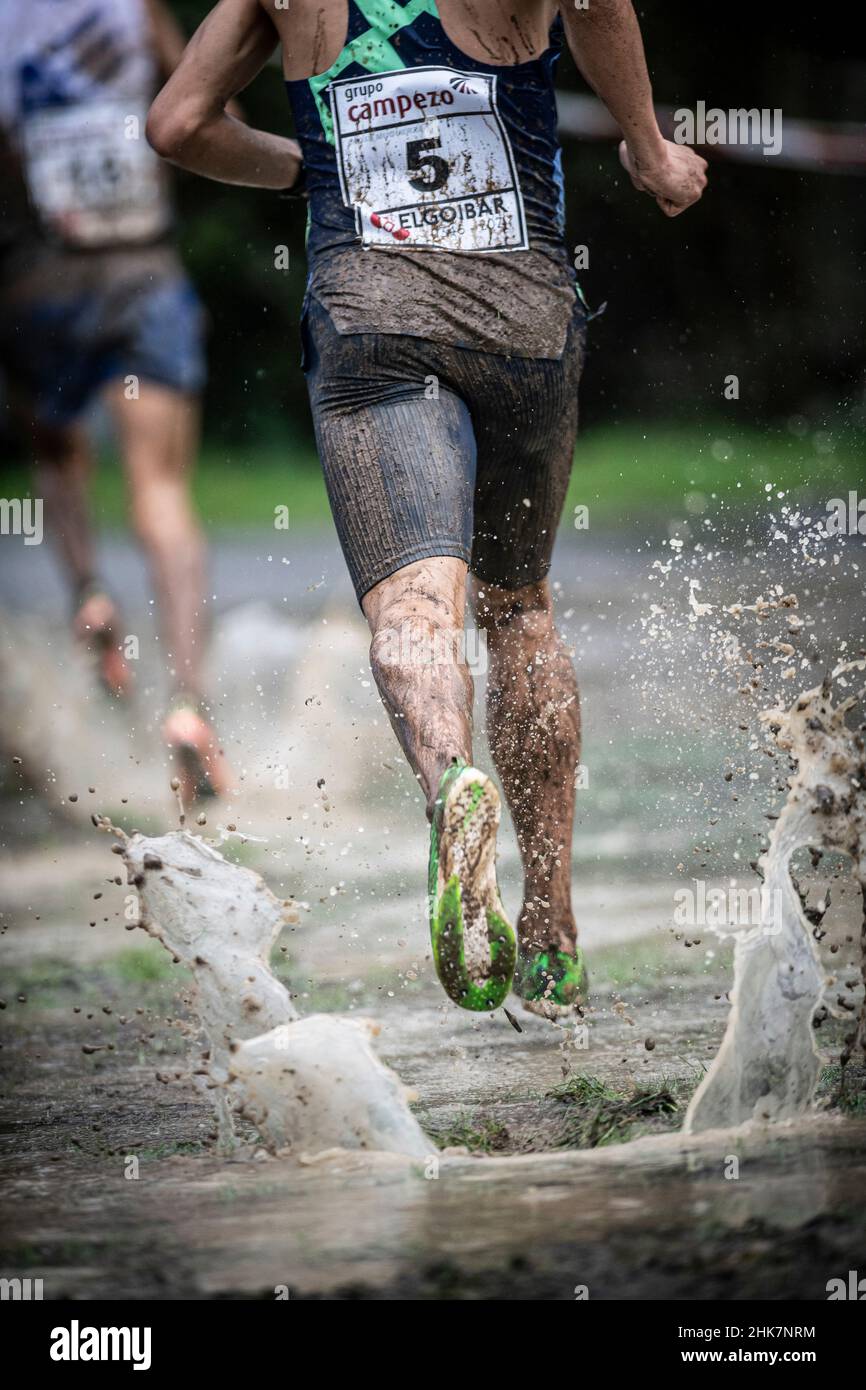 Athlete's legs running in a Cross Country between water and mud, pure ...