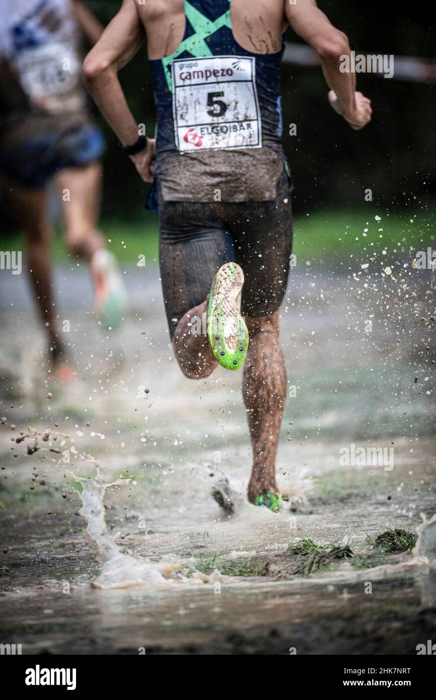 Athlete's legs running in a Cross Country between water and mud, pure ...