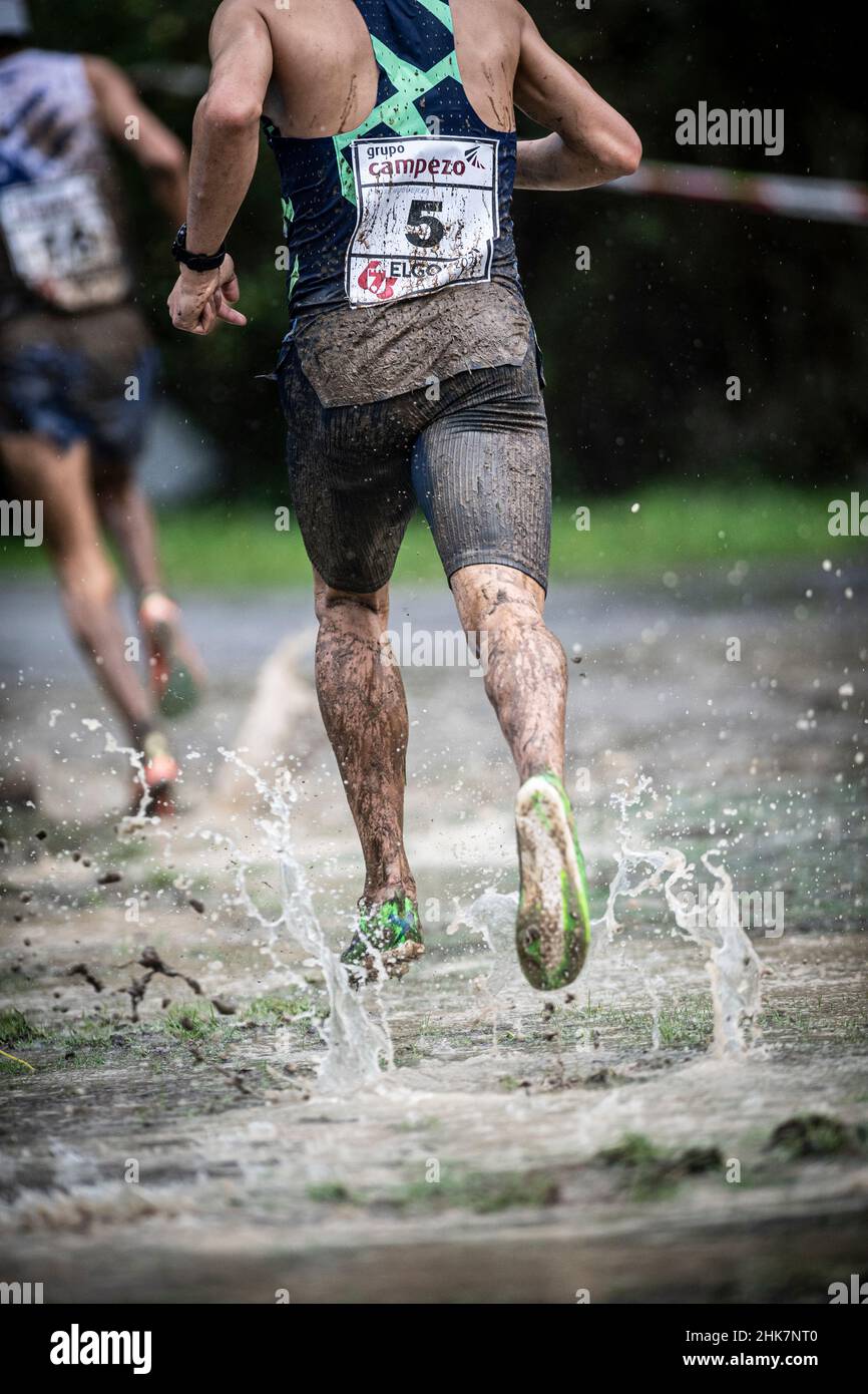 Athlete's legs running in a Cross Country between water and mud, pure ...