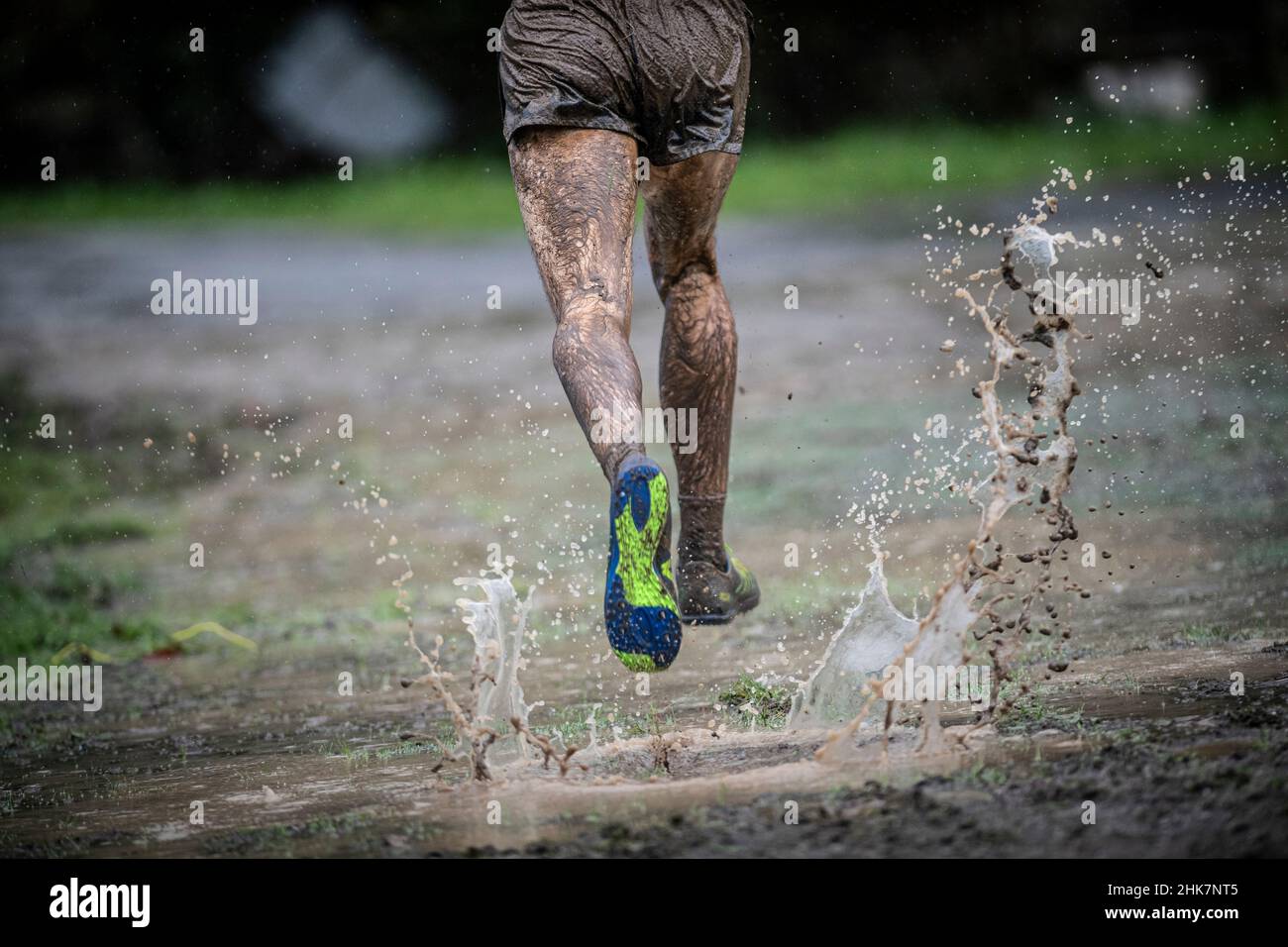 Athlete's legs running in a Cross Country between water and mud, pure ...