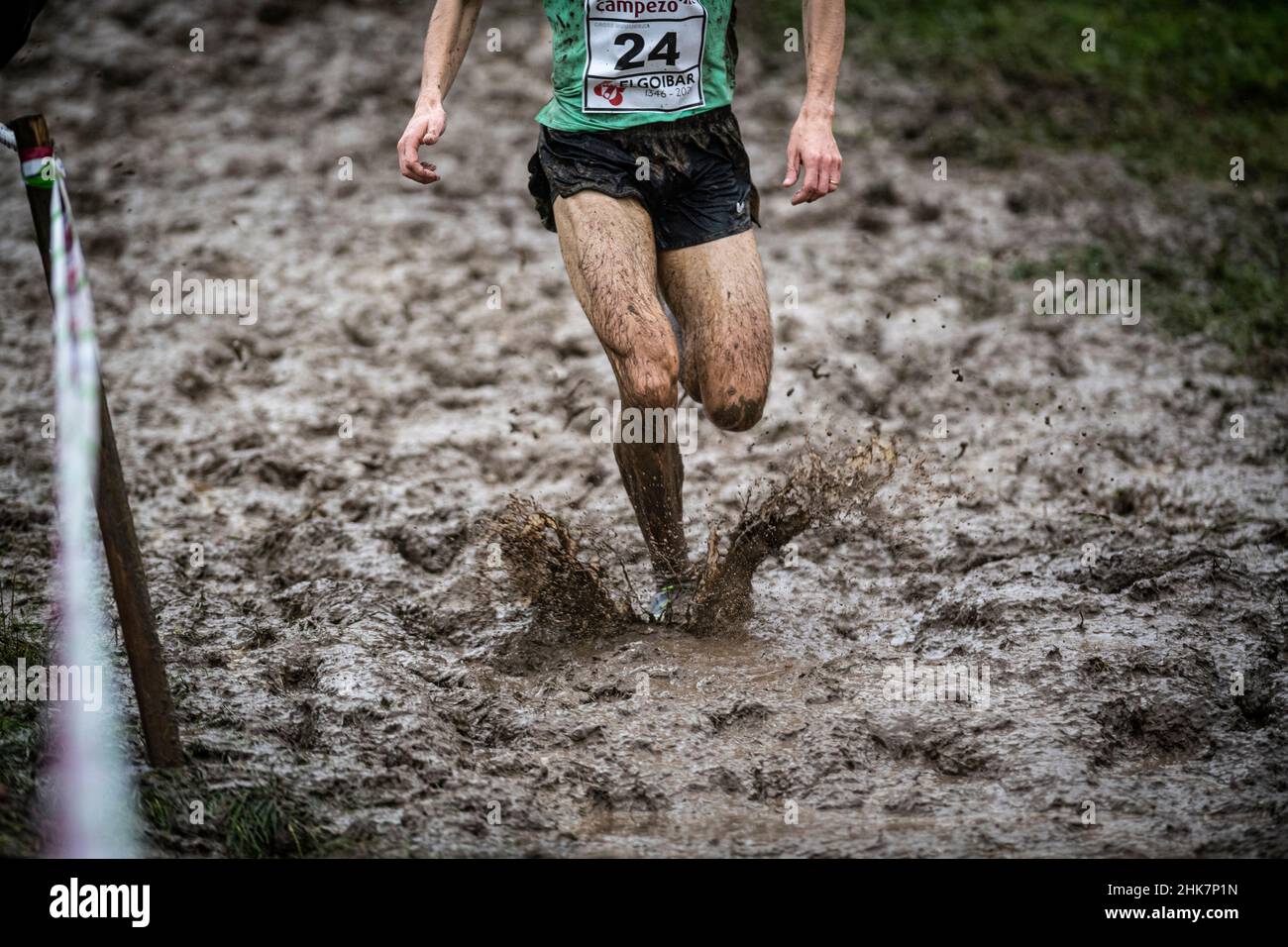 Athlete's legs running in a Cross Country between water and mud, pure ...