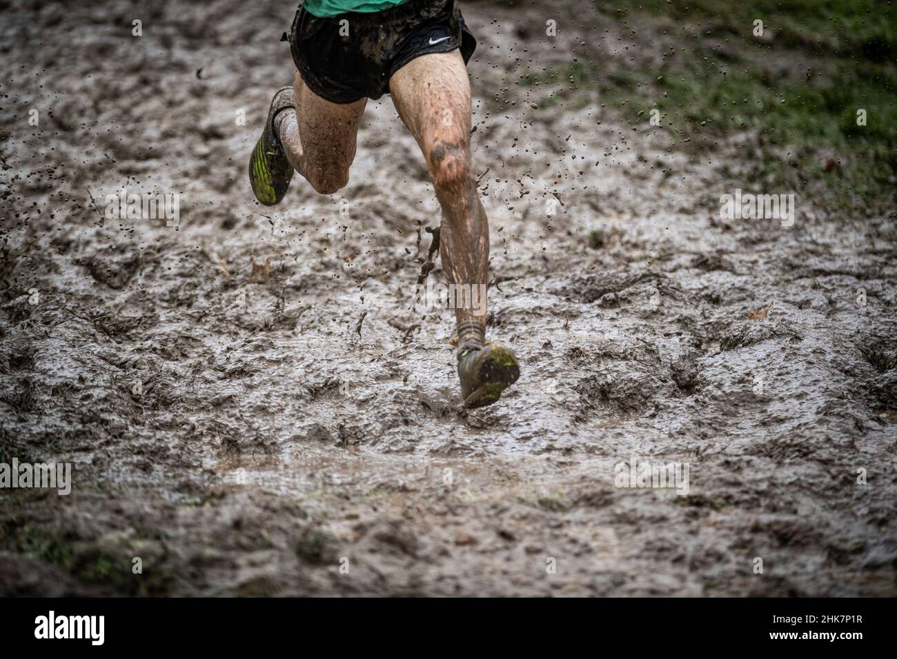 Athlete's legs running in a Cross Country between water and mud, pure ...