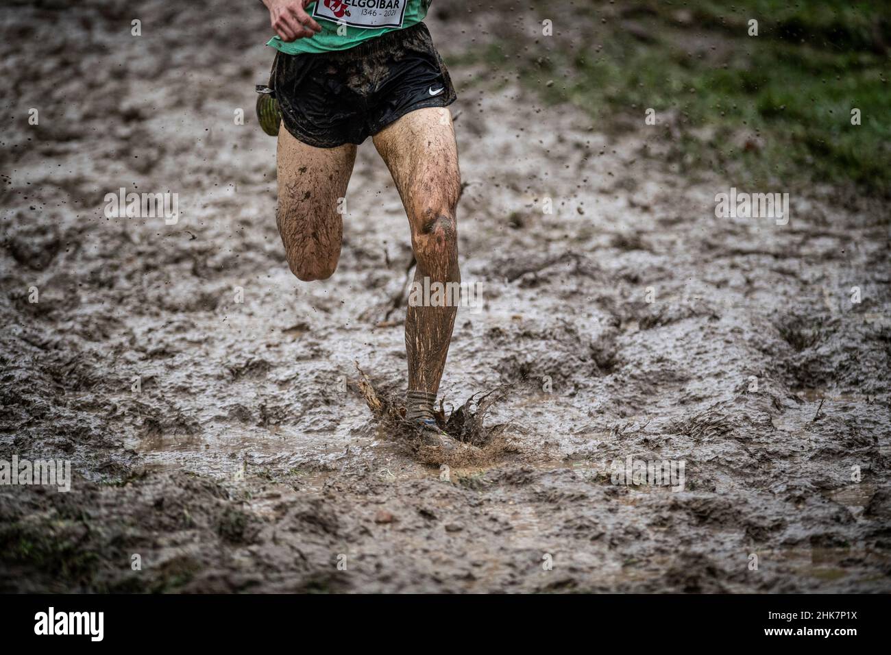 Athlete's legs running in a Cross Country between water and mud, pure ...