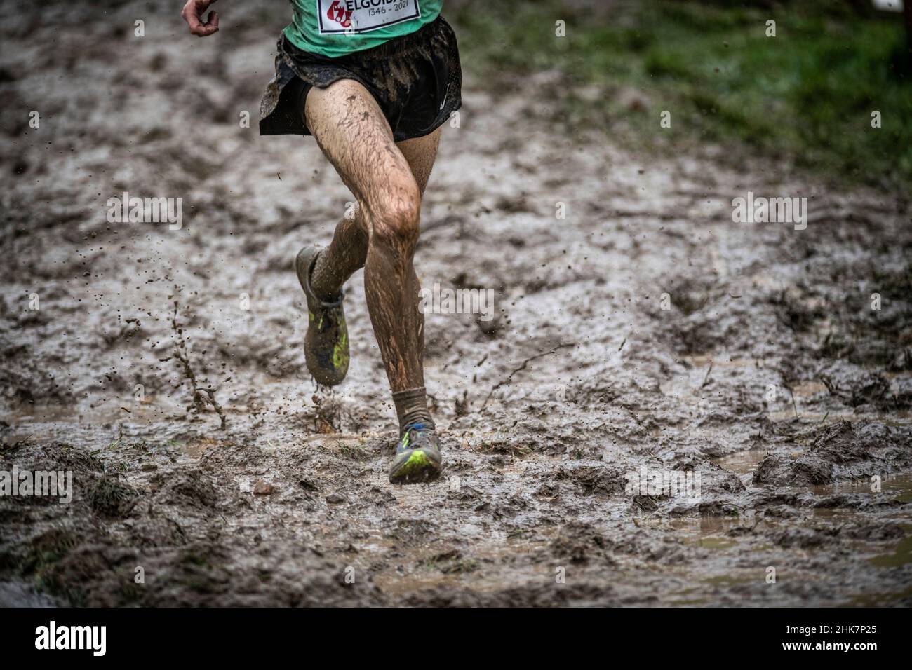 Athlete's legs running in a Cross Country between water and mud, pure ...