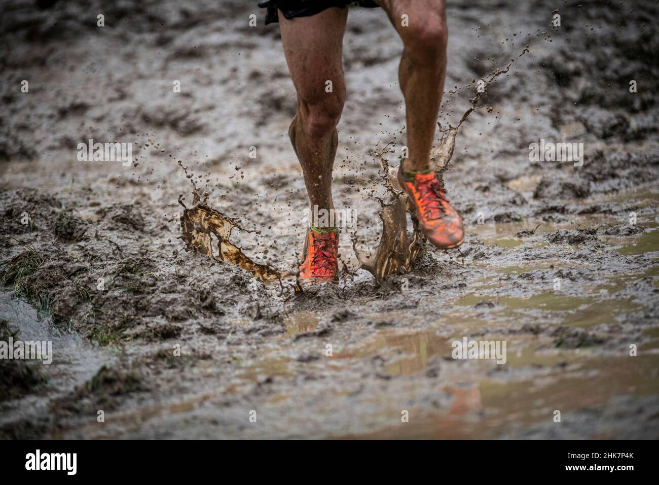 Athlete's legs running in a Cross Country between water and mud, pure ...