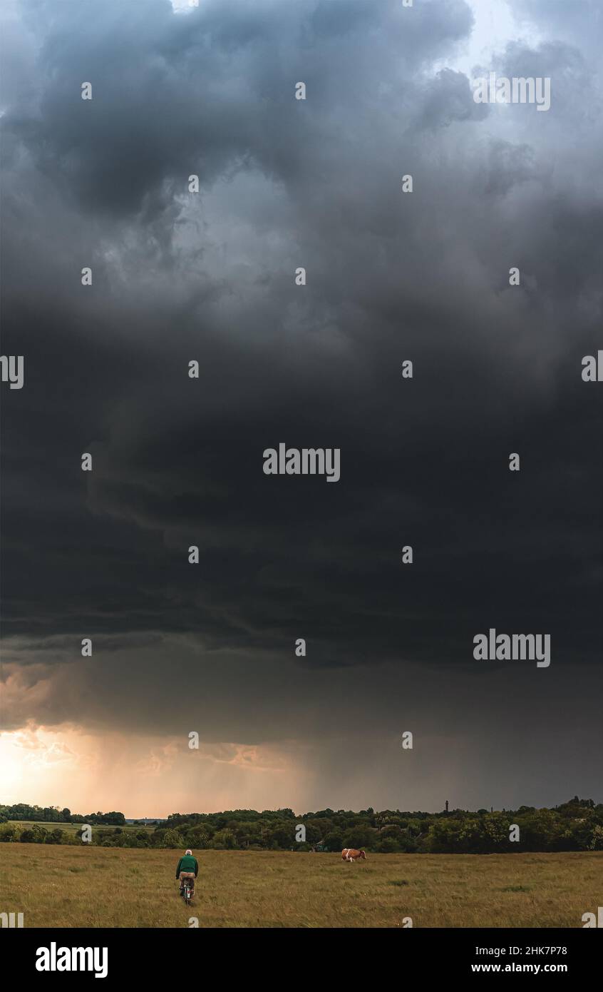 Rain clouds over the village. Shepherd on a bicycle. A man under a ...