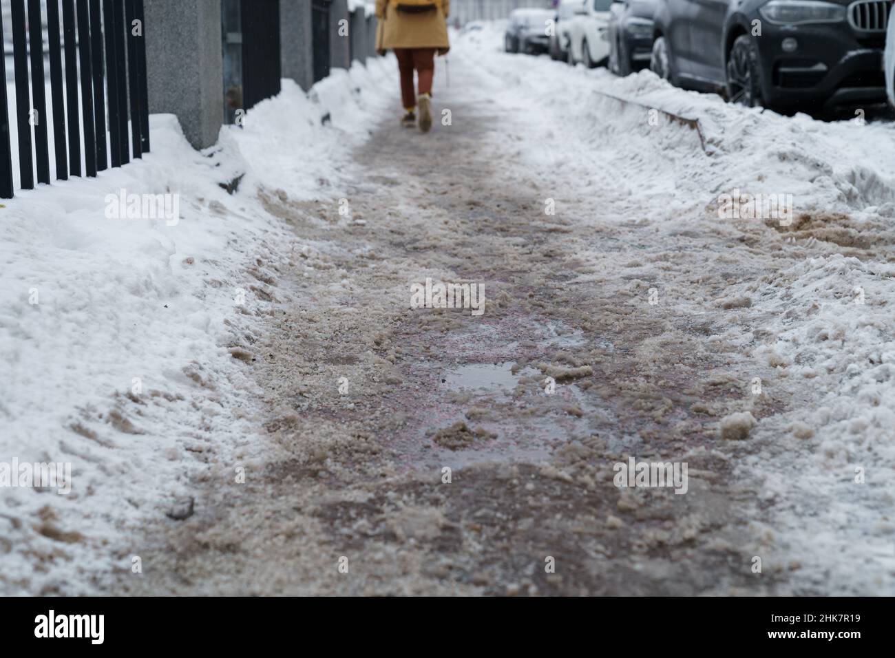 Selective focus on technical salt grains on icy sidewalk surface in ...