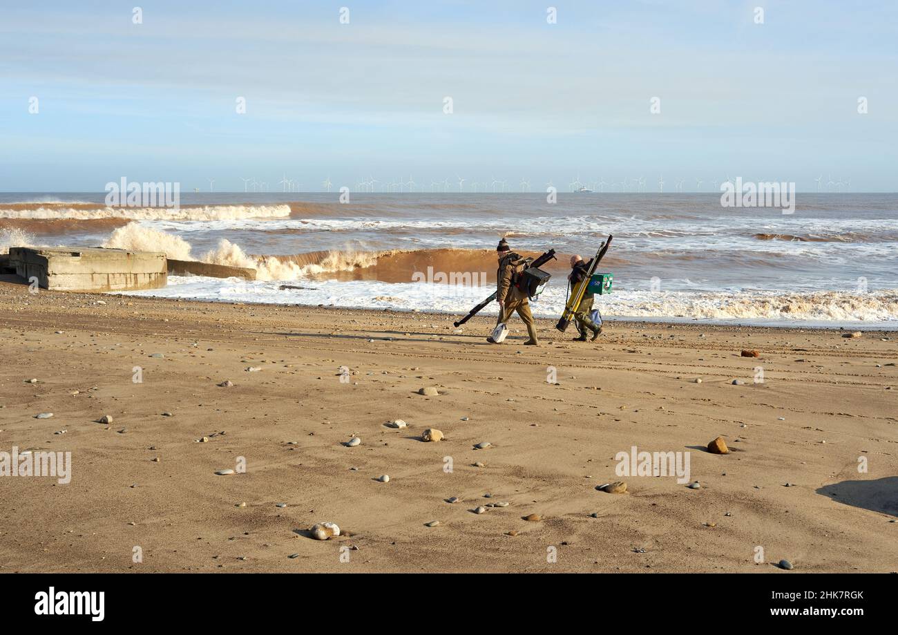 Two anglers walking along a beach Stock Photo - Alamy