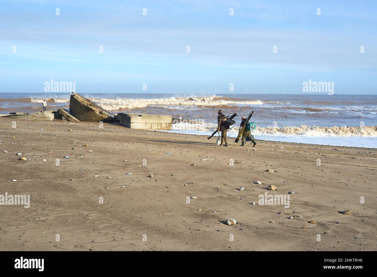Two anglers walking along a beach Stock Photo - Alamy