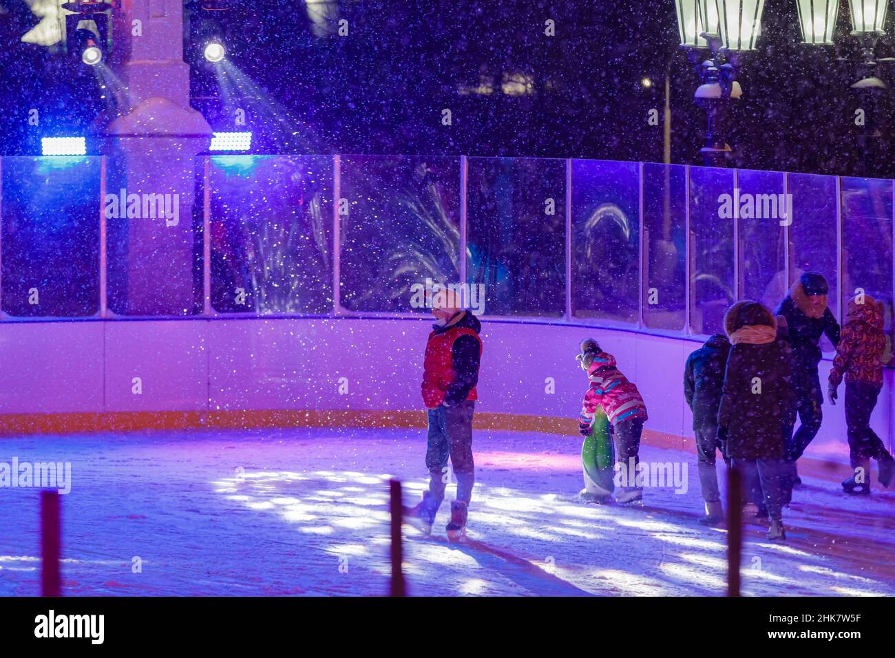 People skate in the evening on a lighted ice rink. A blizzard is raging ...