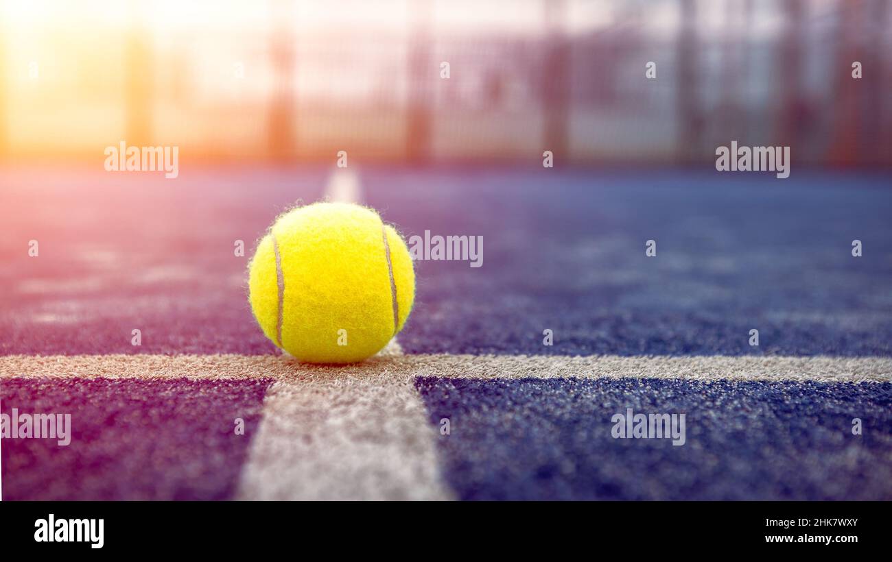 Yellow ball on floor behind paddle net in blue court outdoors. Padel ...