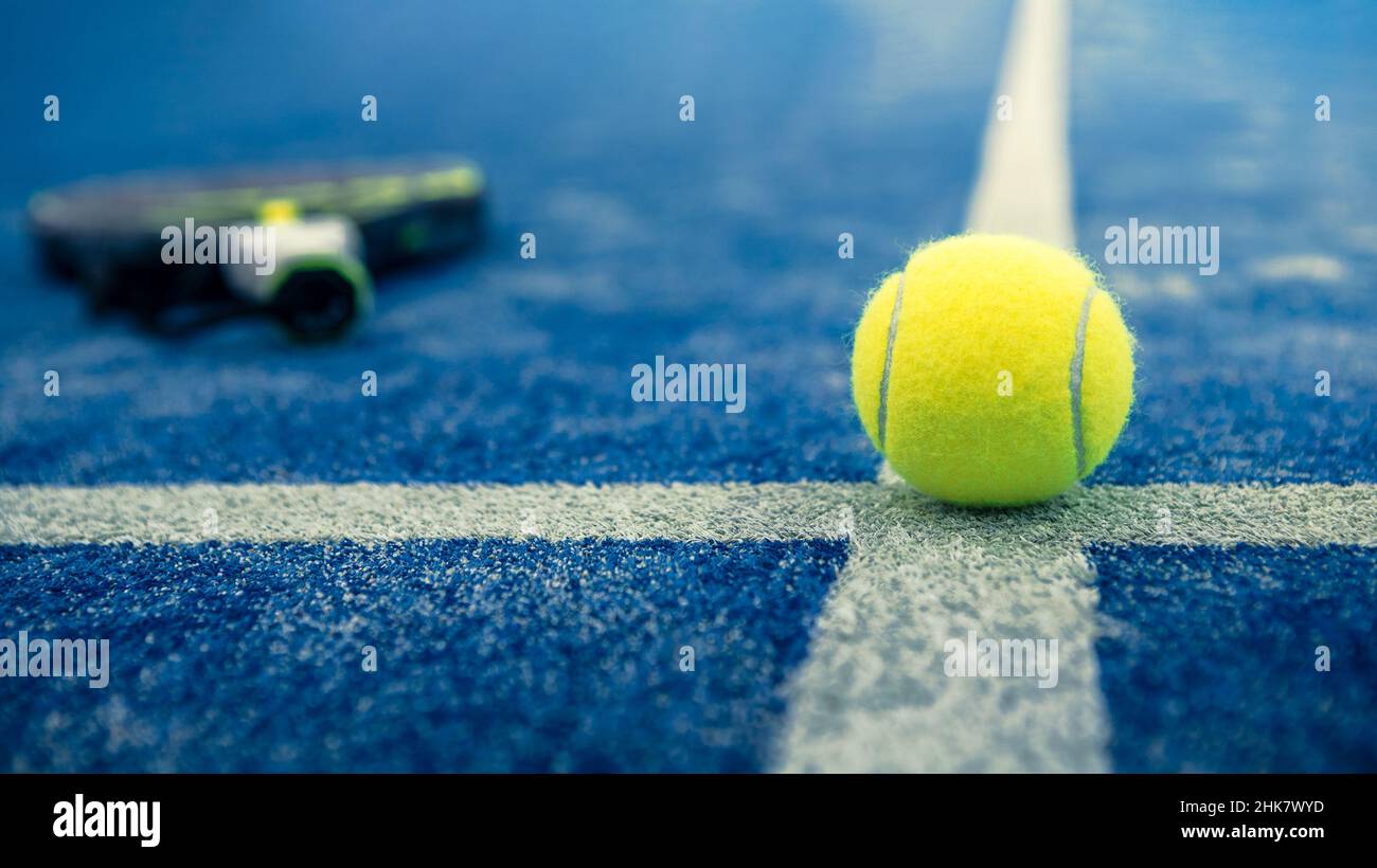 Yellow ball on floor behind paddle net in blue court outdoors. Padel ...