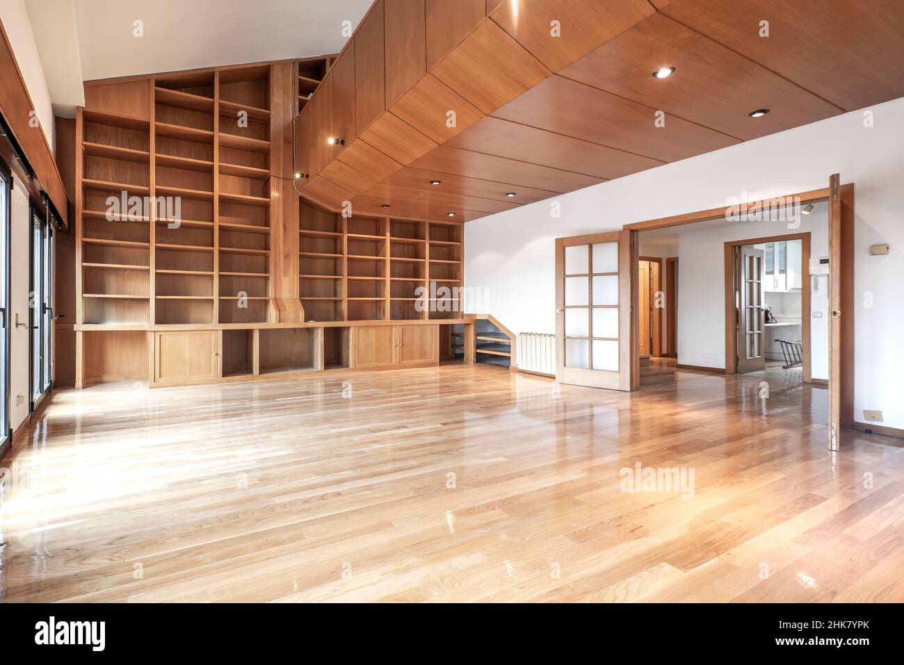 Loft with wall covered by large bookcase in light wood and upper part ...