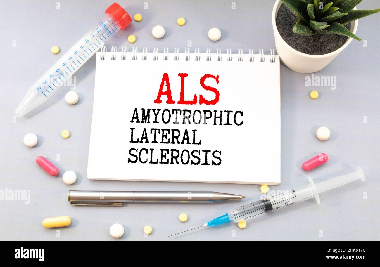 ALS Amyotrophic Lateral Sclerosis written in notebook on white table ...
