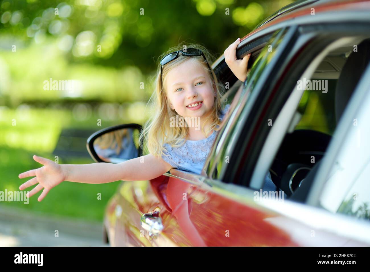 Funny young girl sticking her head out the car window looking forward ...