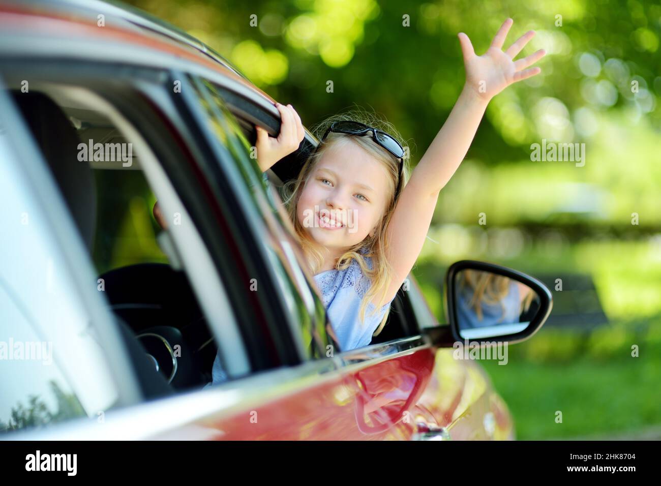 Funny young girl sticking her head out the car window looking forward ...