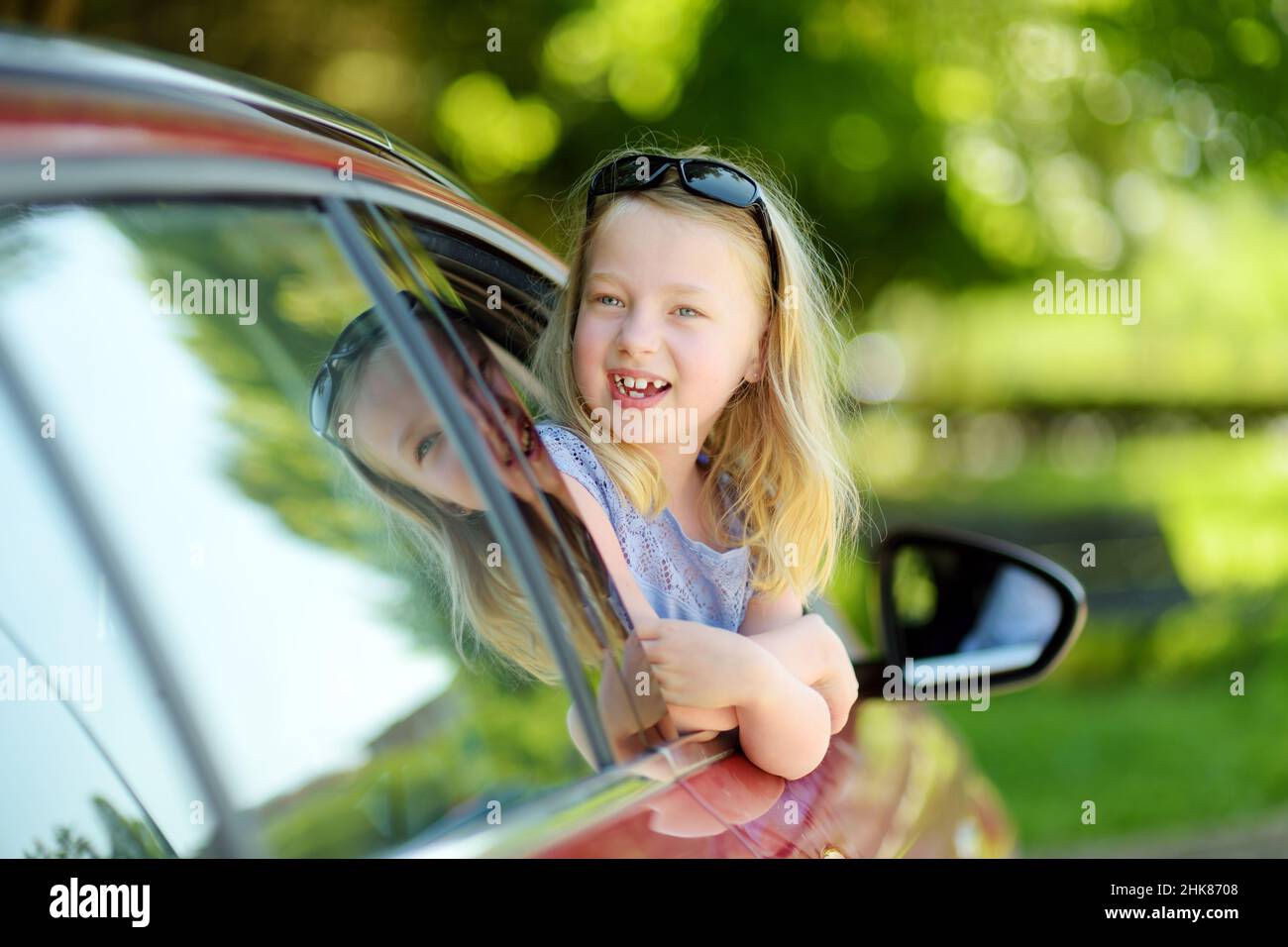 Funny young girl sticking her head out the car window looking forward ...
