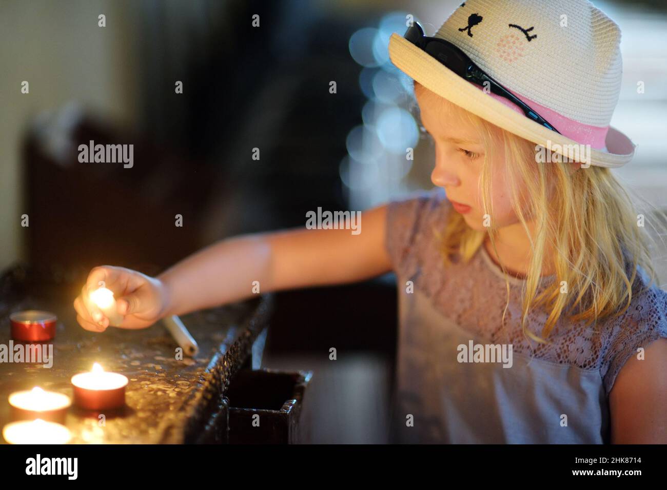 Cute little girl lighting a candle in a church. A child holding small ...