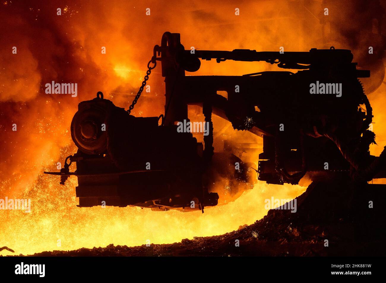 The process of releasing pig iron from a blast furnace. A man works ...