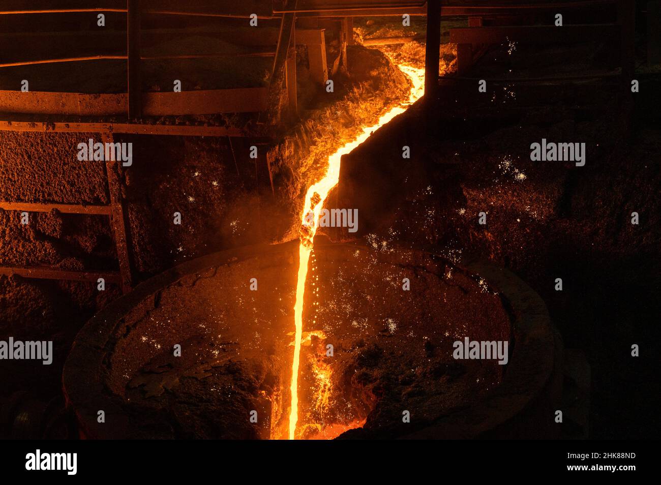 Molten iron flow. Liquid metal is poured into the ladle in a thin ...