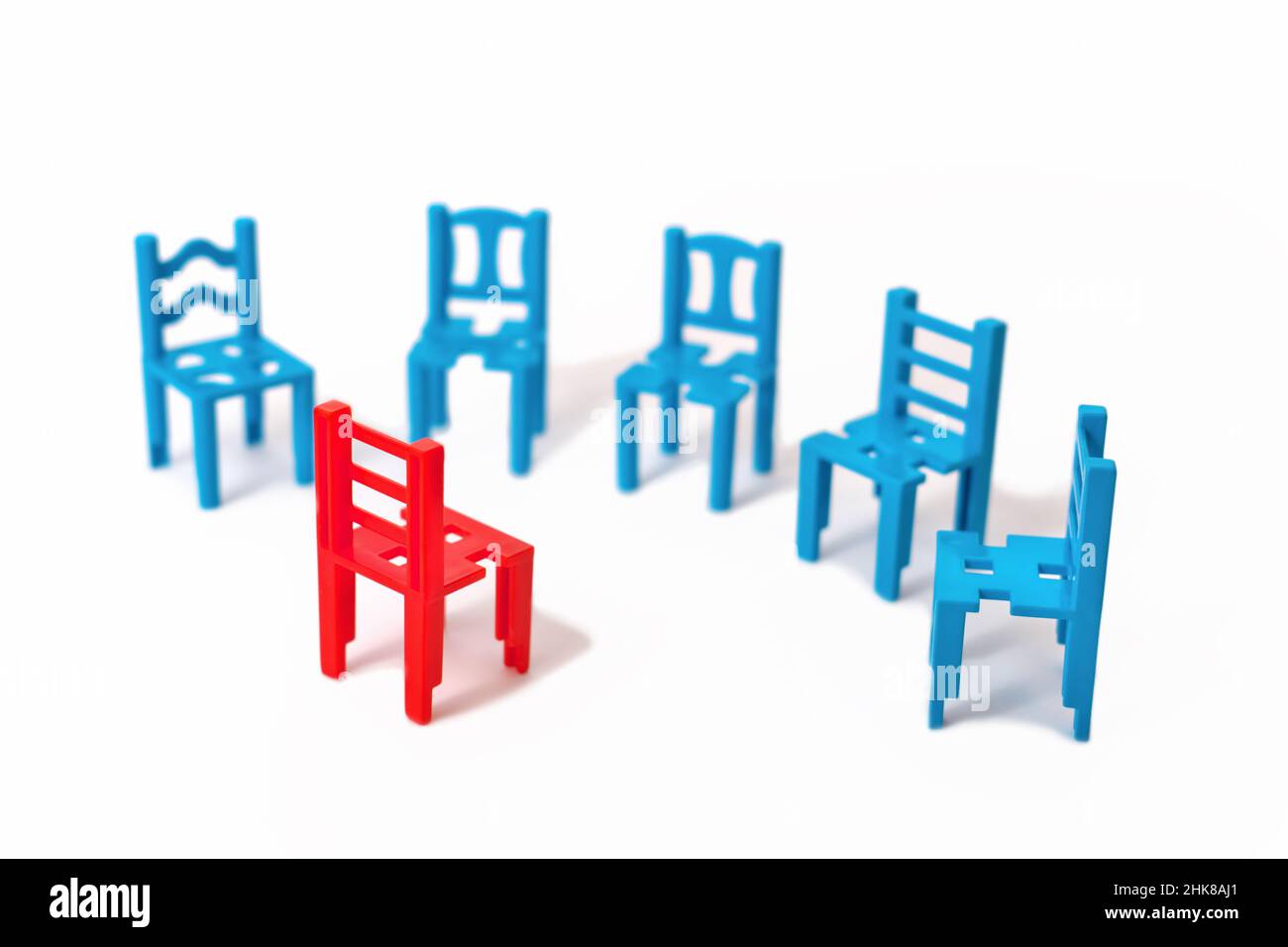 coaching concept. group of blue chairs and one red chair in front of ...
