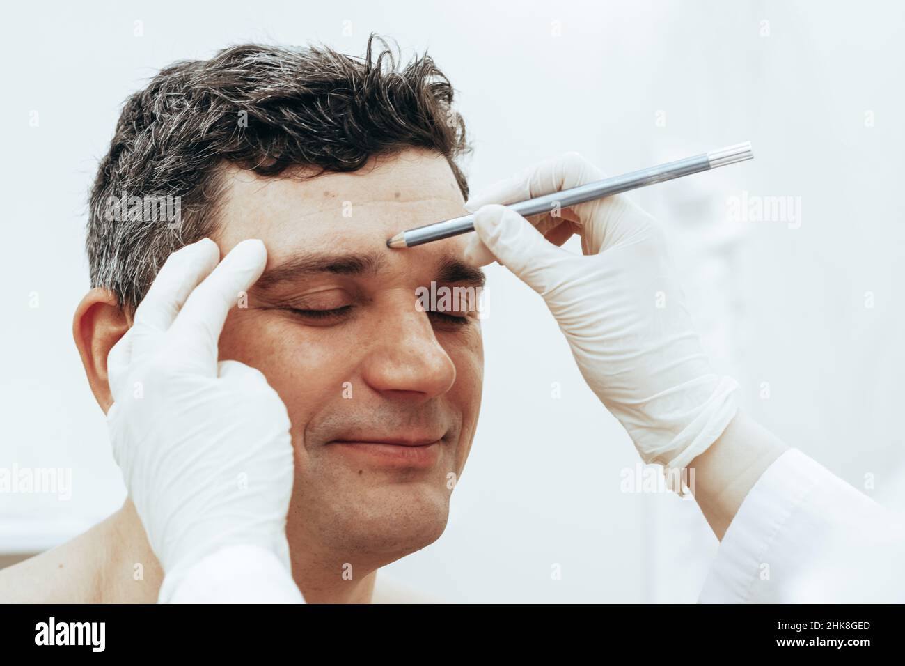 Doctor Cosmetologist prepares man's face for botox injections ...