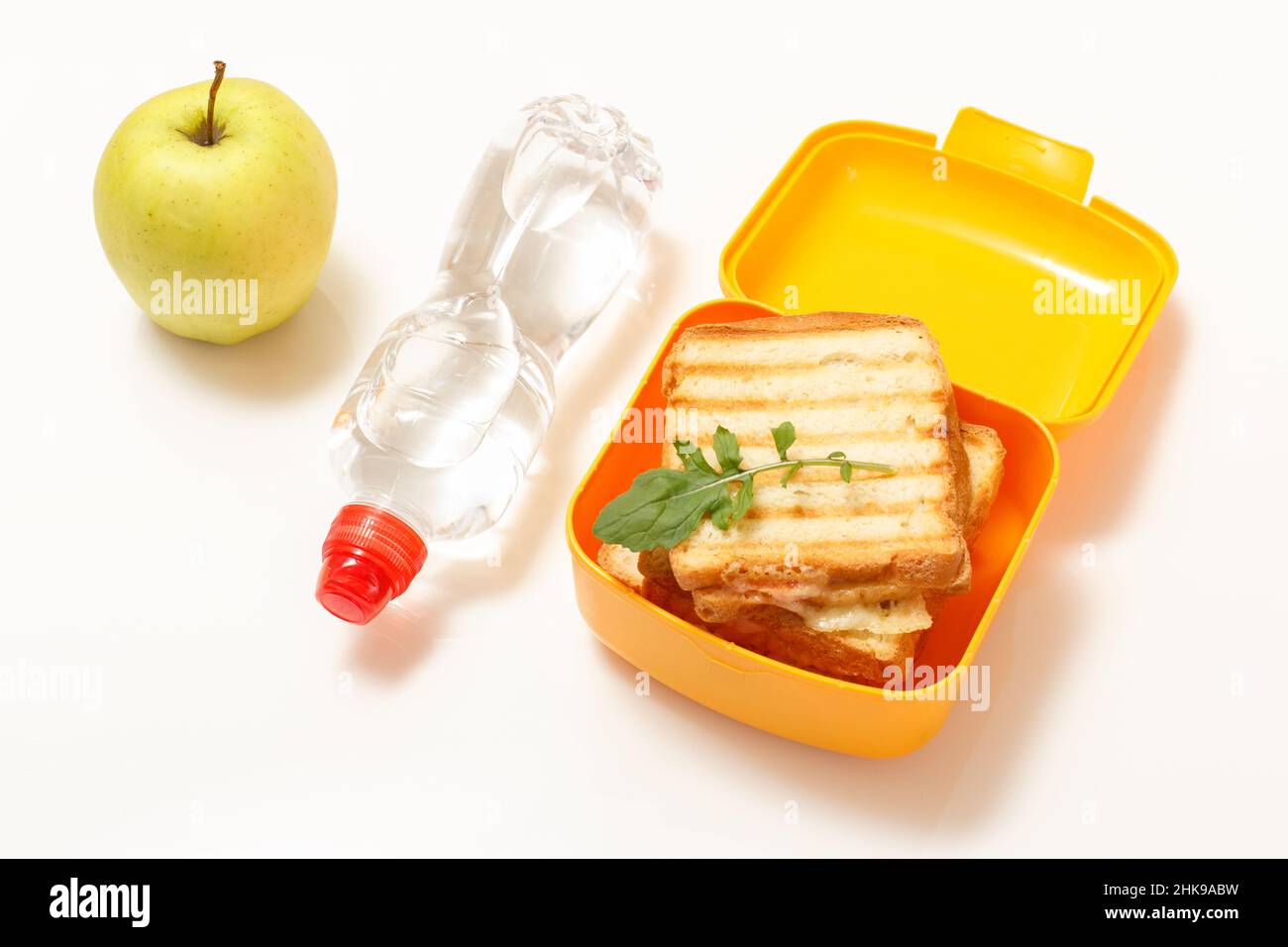 Yellow lunch box with toasted slices of bread, cheese, a bottle of ...