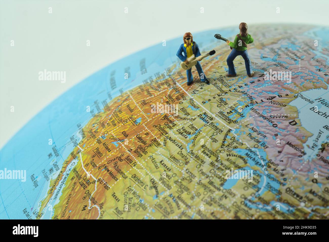 Two miniature musicians with guitar stand on a globe, world music tour ...