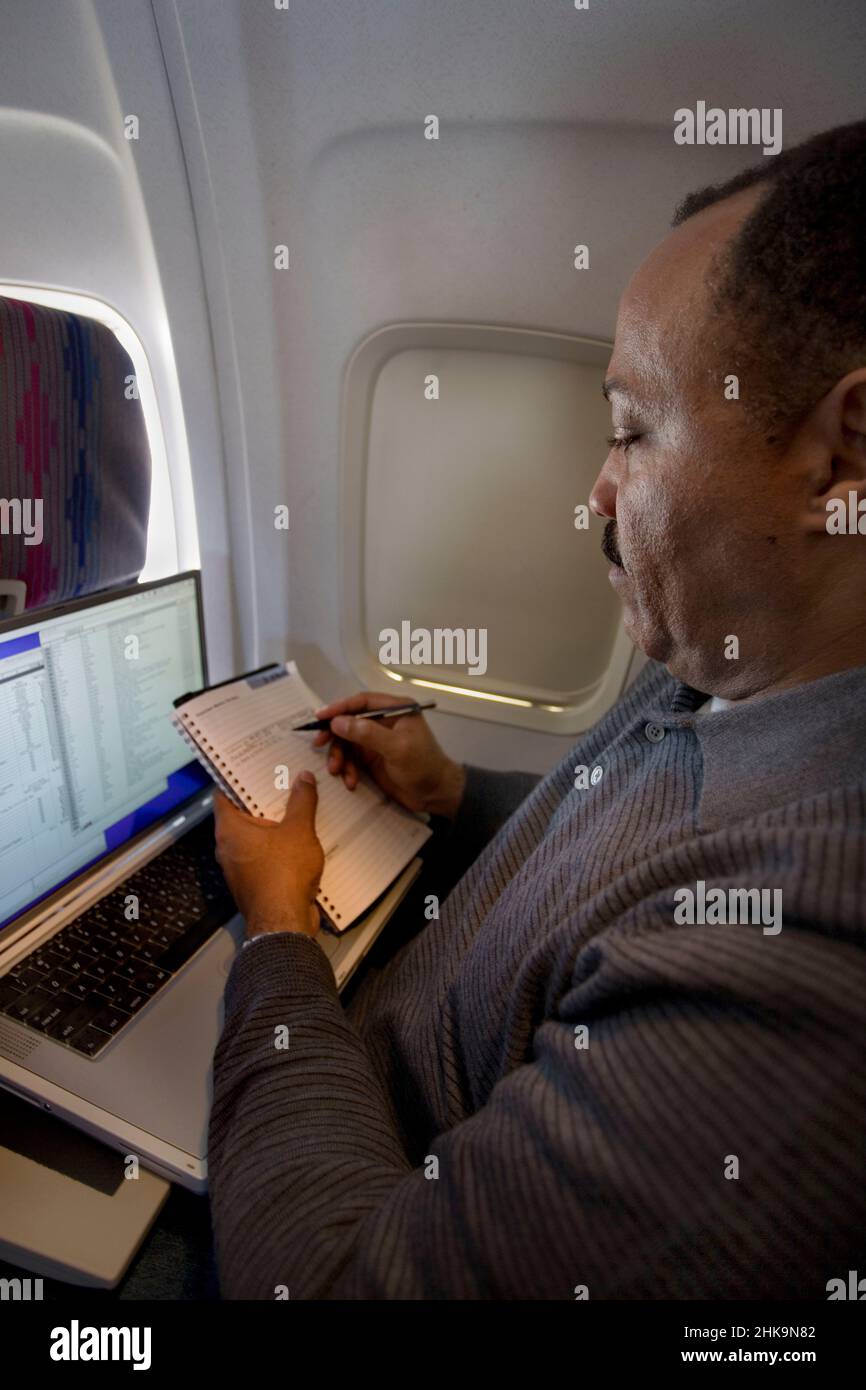 Passenger uses laptop on airliner Stock Photo - Alamy
