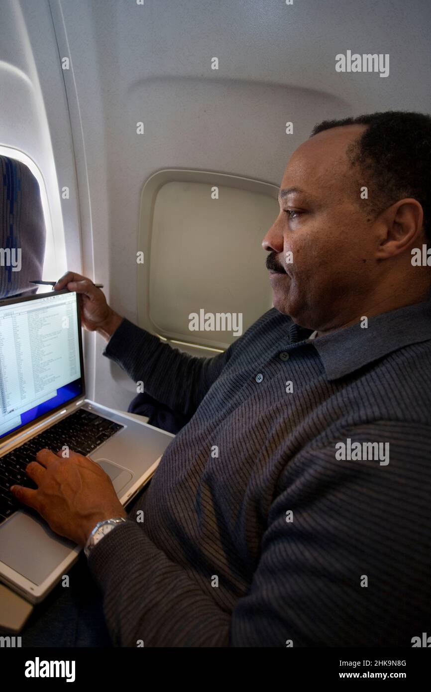 Passenger uses laptop on airliner Stock Photo - Alamy