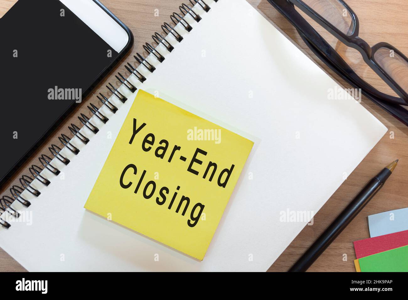Text on yellow note with notepad on wooden desk - Year end closing ...