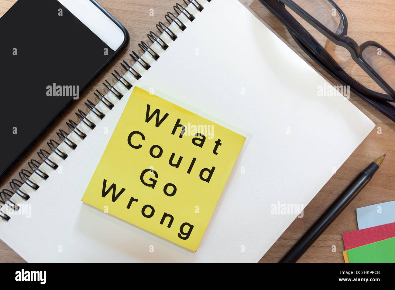 Text on yellow note with notepad on wooden desk - What could go wrong. Business and audit ...