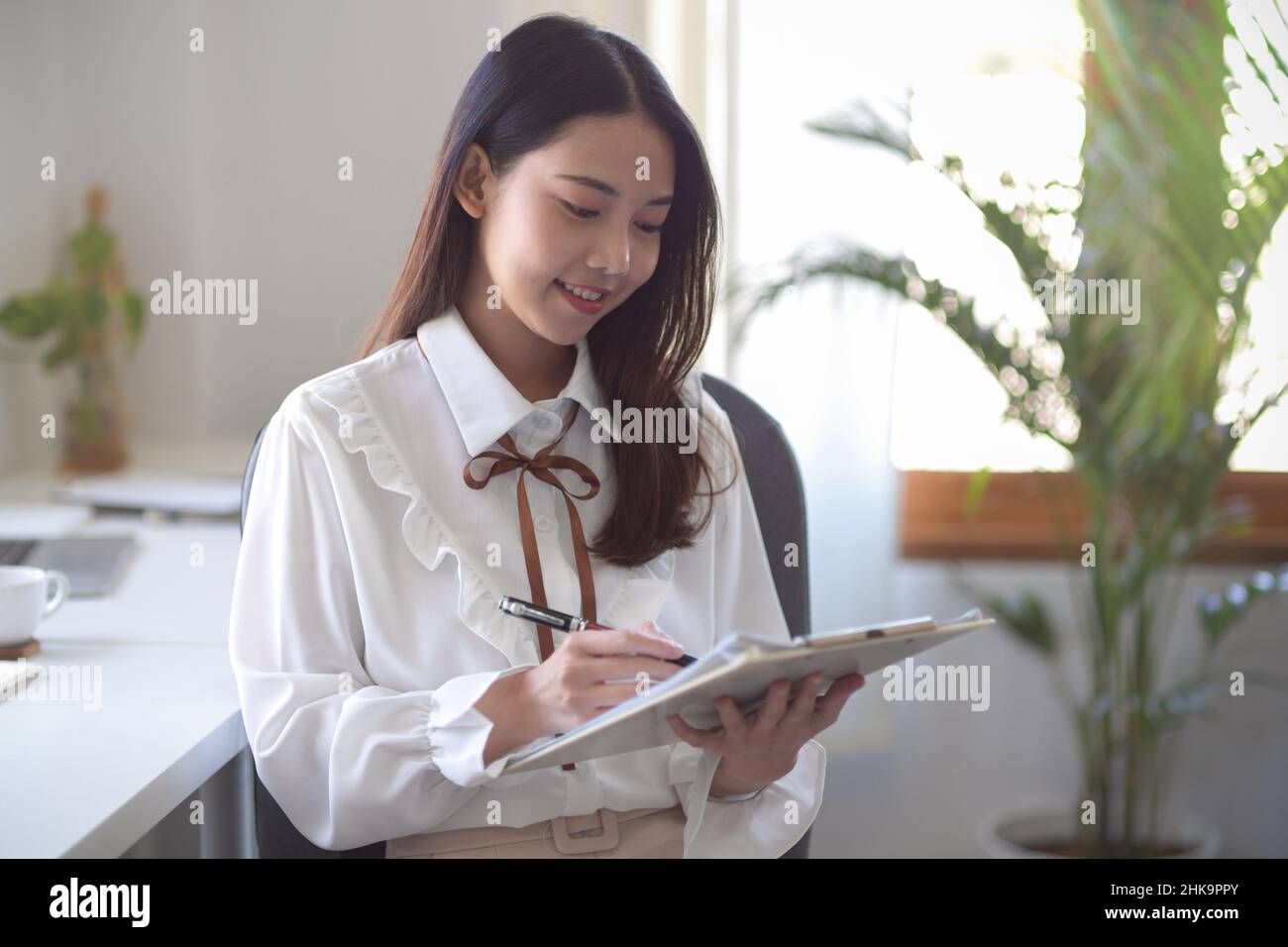 Pretty asian young female officer or business entrepreneur signing her ...
