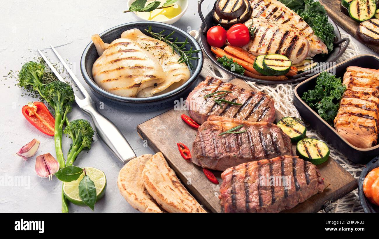 Grilled fish, seafood and meat assortment on light background. Homemade ...