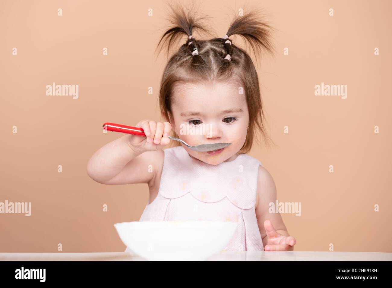 Baby food, babies eating. Portrait of cute Caucasian child kid with spoon. Hungry messy baby ...