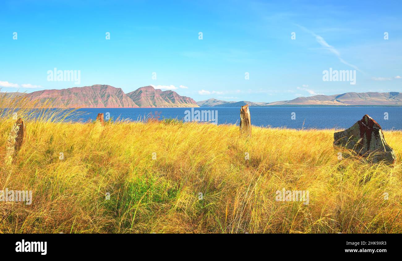 Steppe bank of the Yenisei River, Tepsei Mountain on the horizon under a blue cloudy sky ...