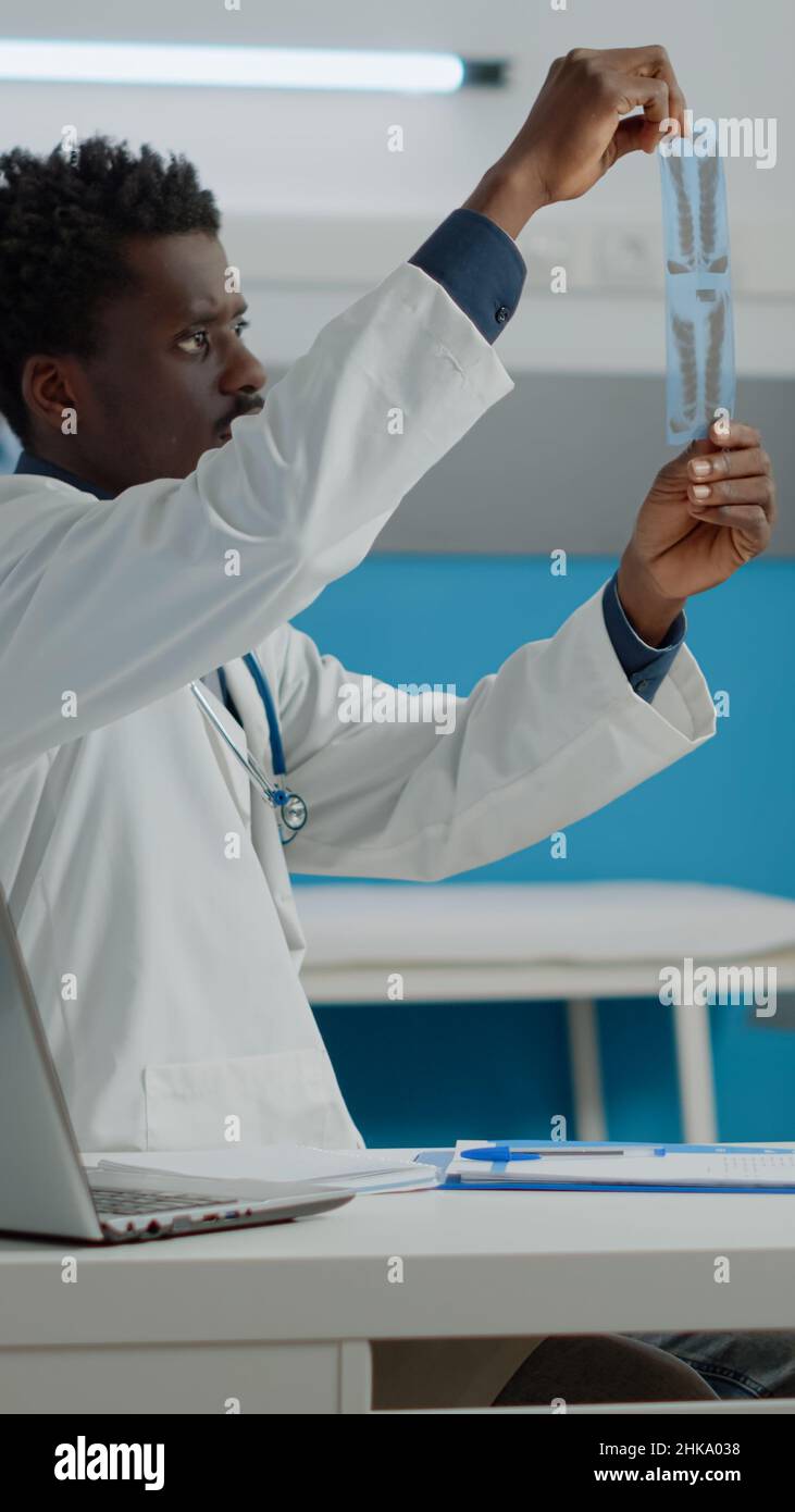 Medic of african american ethnicity analyzing x ray of patient ...