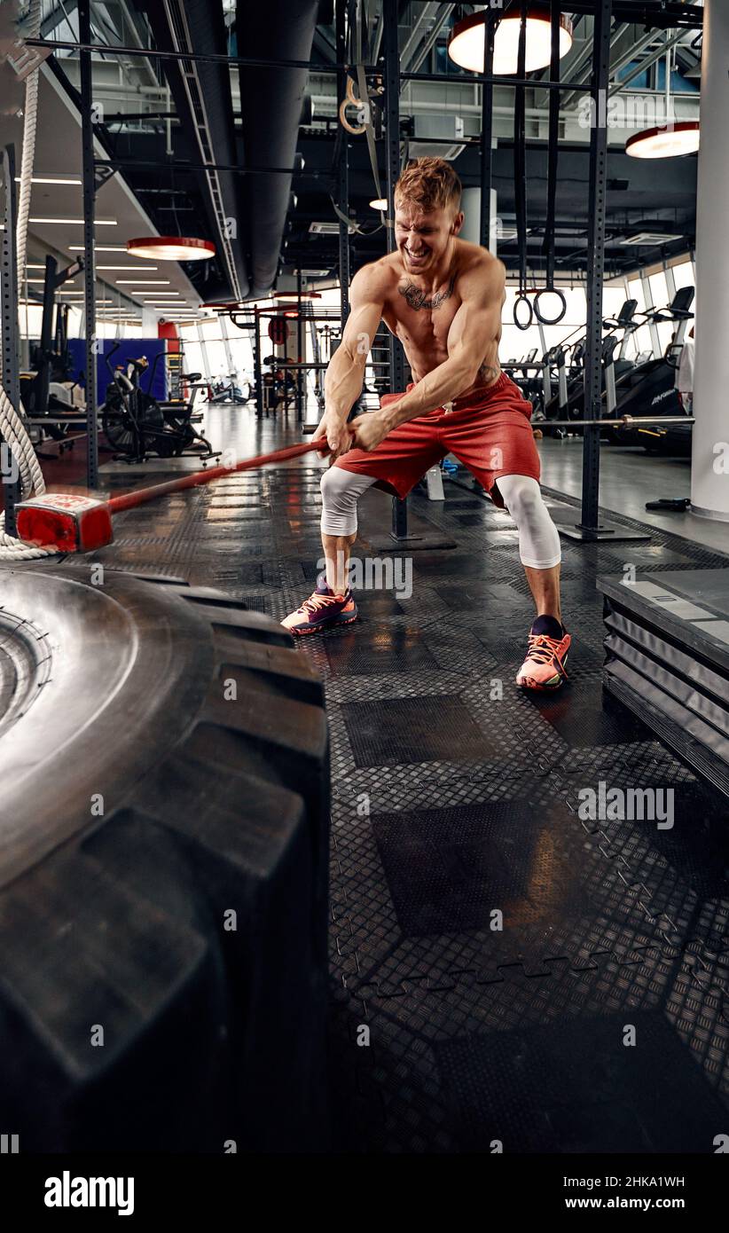 Man fitness training with large and heavy tire hits hammer. Concept ...